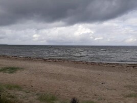 Uma praia com areal e vista para o oceano sob um céu nublado.