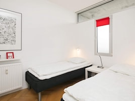 Quarto pequeno e limpo com uma cama, uma escrivaninha e um radiador.