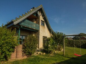 Uma casa com telhado inclinado, varanda e balanço no quintal.