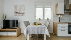 Uma cozinha moderna com armários brancos, forno embutido e um espaço de refeições com mesa posta para dois.
