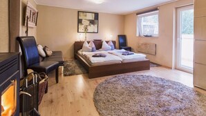 Um quarto com cama, uma poltrona, lareira e um tapete grande.
