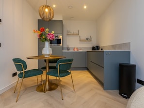 Uma cozinha moderna com área de refeições, apresentando uma mesa redonda, duas cadeiras e um vaso com flores.