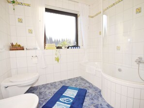 Casa de banho com sanita, lavatório, banheira e janela.