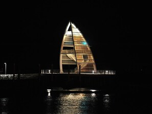 Um edifício moderno com formato triangular e vários níveis, iluminado durante a noite.