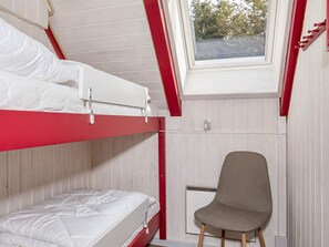 Quarto com beliche, janela, cadeira e radiador.