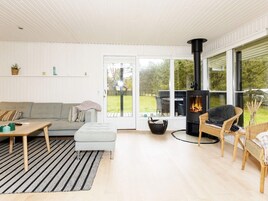 Uma sala de estar moderna com sofá, mesa, lareira e vista para o exterior.