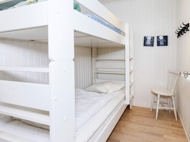 Quarto com beliche, uma cadeira e duas decorações na parede.