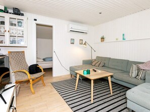 Uma sala de estar com sofá, poltrona, mesa e abajur.