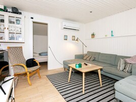 Uma sala de estar com sofá, poltrona, mesa e abajur.
