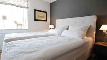 Quarto de hotel com duas camas, uma janela com vista para um edifício e um quadro na parede.