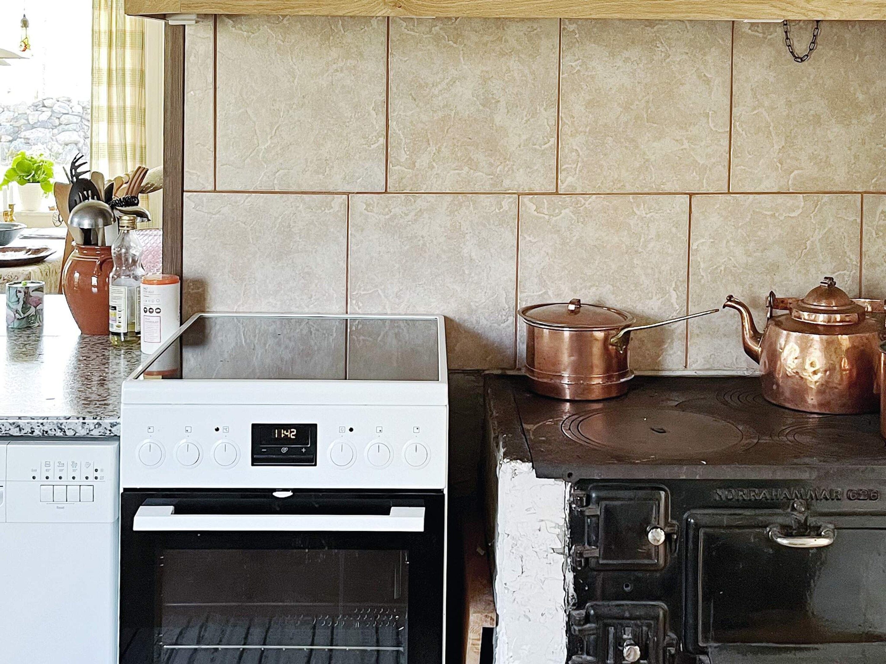 Cozinha com forno branco, fogão preto e utensílios de cobre.