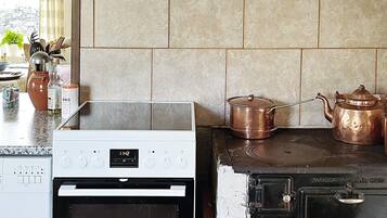Cozinha com forno branco, fogão preto e utensílios de cobre.