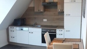 Uma cozinha moderna com armários brancos, bancada de madeira e um espaço de refeições com mesa e cadeiras.