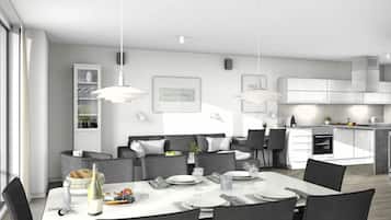 Uma cozinha moderna com armários brancos, uma área de jantar com mesa branca posta para quatro pessoas e uma sala de estar com sofá e poltronas.