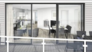 Um interior moderno com sala de jantar, cozinha e área de estar visíveis através de grandes portas de vidro deslizantes.