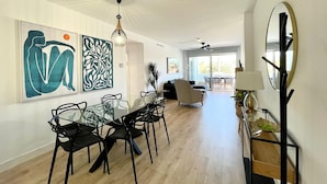 Uma sala de jantar moderna com mesa de vidro, cadeiras pretas e obras de arte contemporâneas nas paredes.