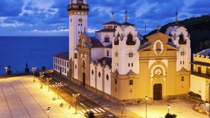 Igreja costeira com uma torre de sino imponente e várias cúpulas, localizada à beira-mar.
