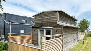 Uma cabana de madeira moderna com varanda, janela e porta.