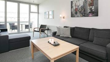 Uma sala de estar moderna com um sofá, uma mesa de centro e uma pintura de paisagem urbana na parede.