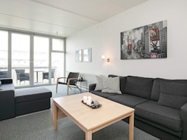 Uma sala de estar moderna com um sofá, uma mesa de centro e uma pintura de paisagem urbana na parede.