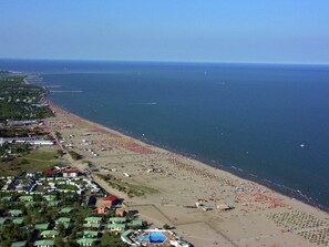 Vista aérea de uma praia com vários guarda-sóis e pessoas.