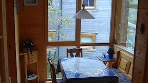 Quarto compacto com uma mesa de jantar, cadeiras, uma pequena janela e um banco de madeira.