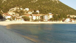 Uma área costeira com edifícios numa encosta e uma praia ao primeiro plano.