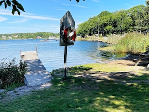 Vista do lago com um píer, mesa de piquenique e um flutuador em um poste.