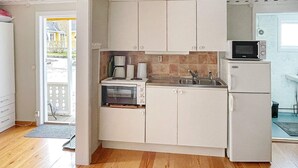 Cozinha compacta com armários brancos, micro-ondas, máquina de café e pia.