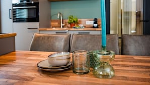 Uma cozinha moderna com uma vela verde-água, um jarro de vidro e um conjunto de pratos sobre uma mesa de madeira.