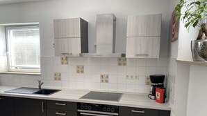 Uma cozinha moderna com armários escuros, forno embutido, fogão e máquina de café.