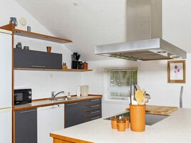 Cozinha moderna com forno embutido, cafeteira e janela com persianas.