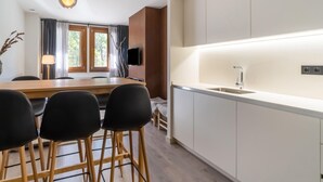 Uma cozinha moderna com mesa de jantar de madeira, banquetas, pia embutida e televisão fixada na parede.