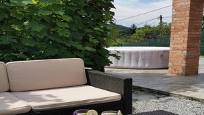 Um pátio com um sofá, duas bebidas sobre uma mesa e uma área coberta com um logotipo.