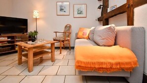 Uma sala de estar aconchegante com sofá, poltrona, mesa de centro de madeira e televisão de tela plana.