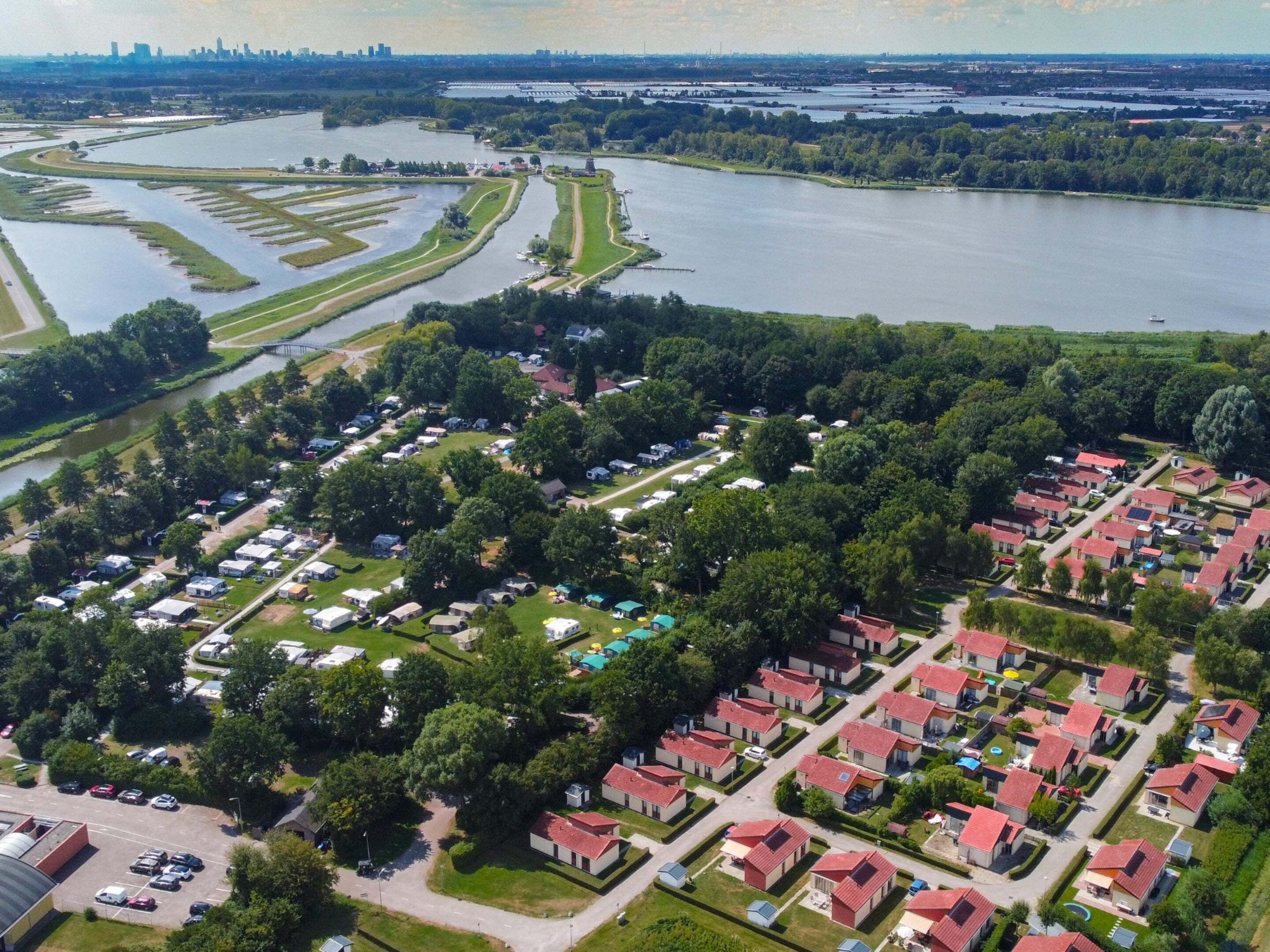 Vista aérea de uma área residencial com um lago, mostrando construções organizadas e um estacionamento.