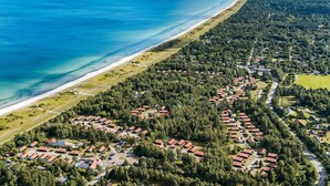 Vista aérea de uma área residencial à beira-mar, com casas e uma praia.