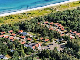 Vista aérea de uma área residencial com casas, praia e estacionamento.