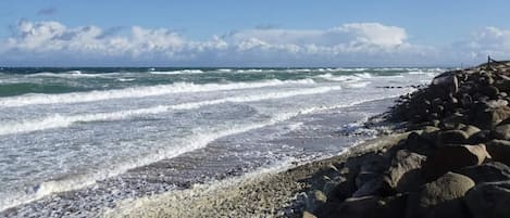 Uma praia rochosa com ondas quebrando na costa.