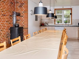 Uma cozinha moderna com parede de tijolos, fogão e área de refeições com uma mesa comprida e cadeiras.