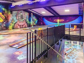 Um espaço temático para brincar com escorrega, parede de escalada e um mural de estação espacial.