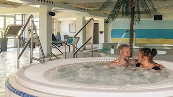Uma banheira de hidromassagem com duas pessoas, área de estar interna e uma palmeira.
