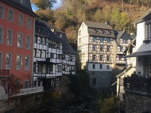 Uma cidade europeia tradicional com casas de enxaimel, uma ponte de pedra e um rio.