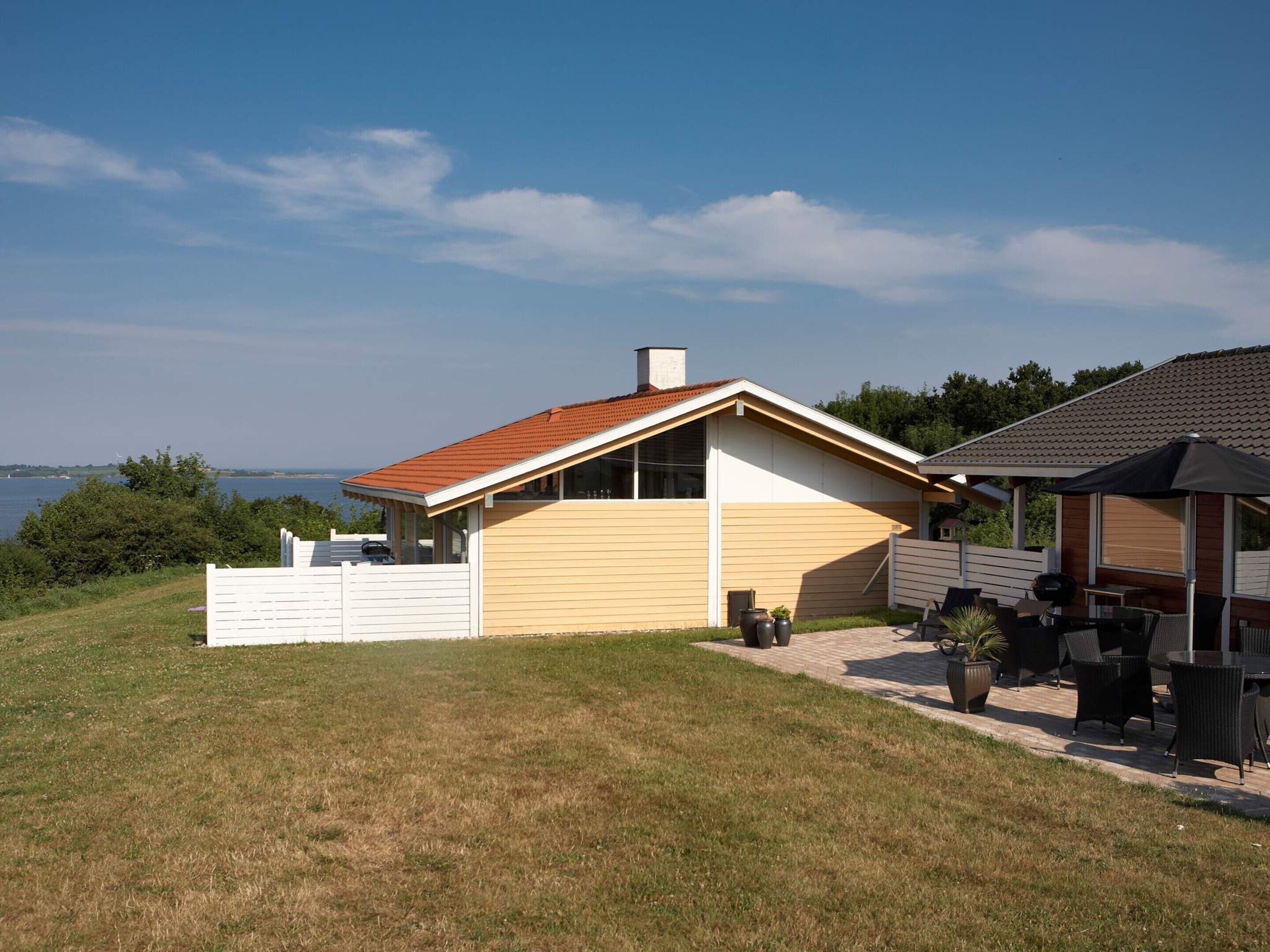 Uma casa moderna com telhado inclinado, quintal cercado e mobiliário de exterior.