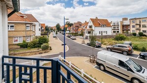 Rua residencial com casas, carros estacionados e uma van.