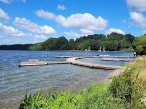 Um lago com um cais e um píer, cercado por vegetação e árvores.