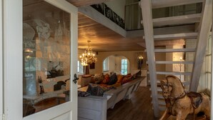 Um quarto amplo com escada de madeira, um candelabro e um cavalinho de balanço de madeira.
