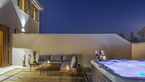 Terraço no telhado com hidromassagem, área de estar e uma pequena mesa com velas.