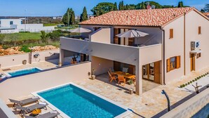 Uma casa moderna de dois andares com piscina, área de estar externa e vista para a paisagem ao redor.