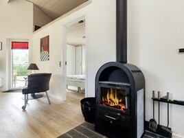 Um interior moderno com lareira a lenha, área de jantar e quarto.